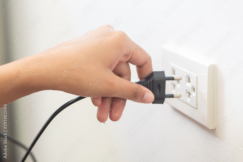 using electricity wall outlet with wet hand; electrocute danger concept ...