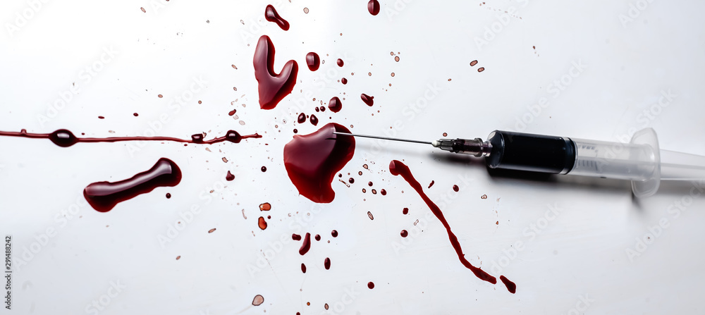 Syringe and blood splatter on a white background. A lot of blood and a ...