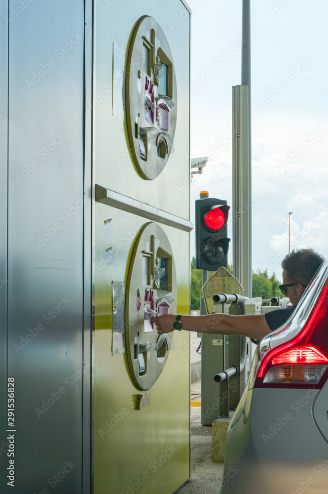 vertical view of a man taking ticket from a toll booth on a French ...