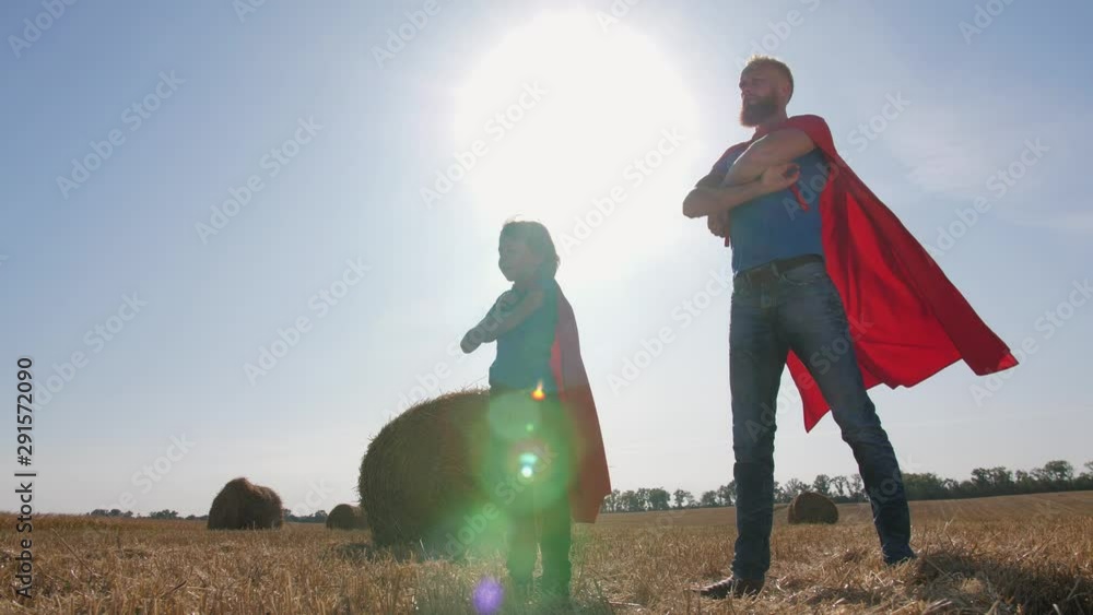 Bearded father and cute little son in superhero costumes standing in ...