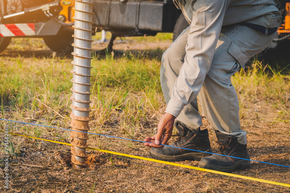 technician installing ground screw for mounting structure of solar ...