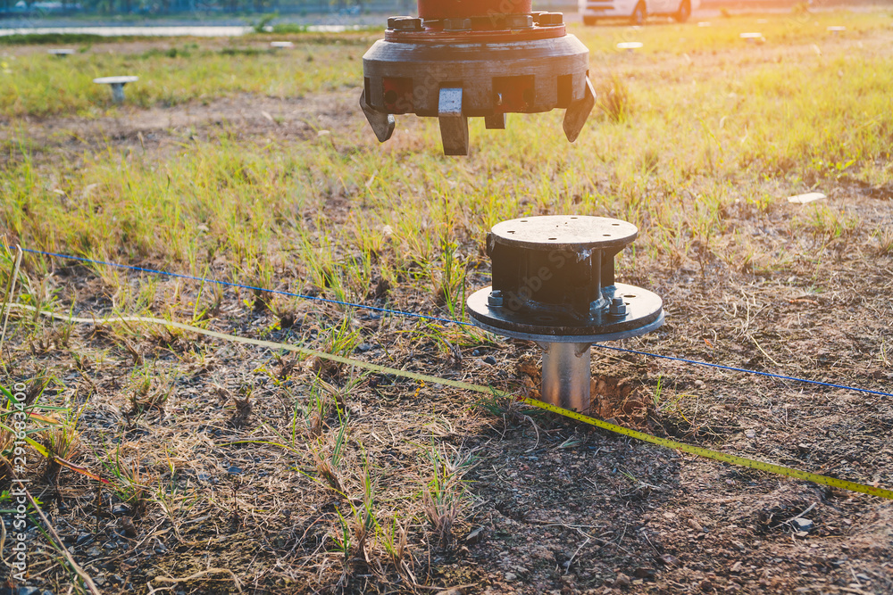 technician installing ground screw for mounting structure of solar ...
