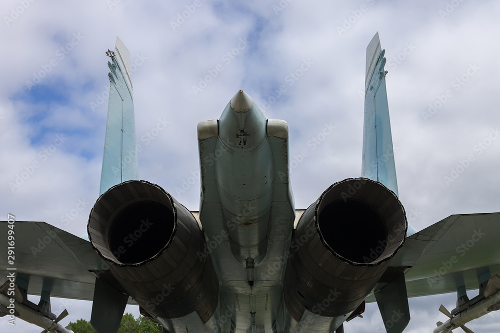 The tail of a military fighter and its two large jet engine nozzles ...