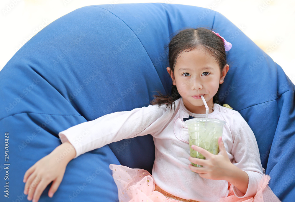 Happy little Asian child girl drinking iced Matcha Green Tea lying on ...