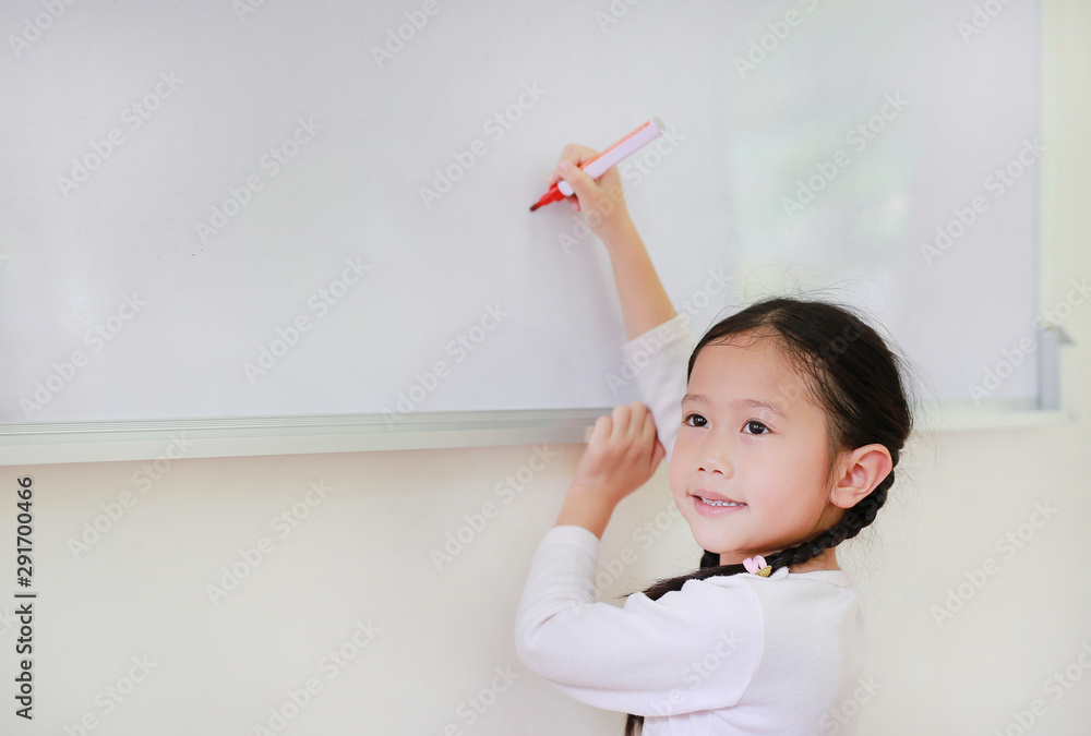 Portrait of Smiling little Asian child girl or Schoolgirl writing ...