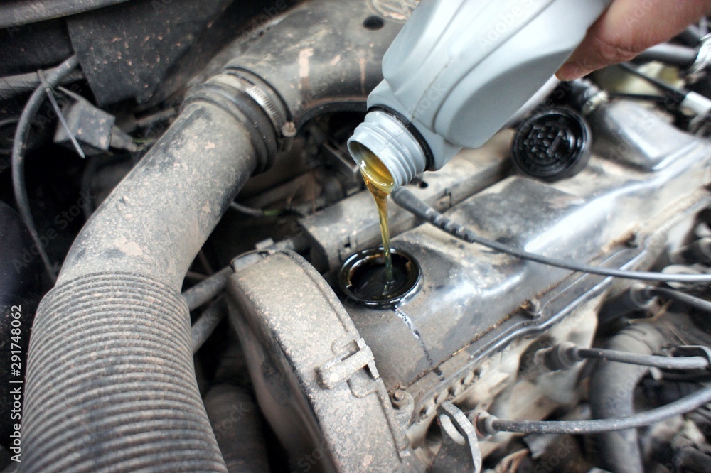 car services. maintenance on vehicle. pouring oil in the car engine ...