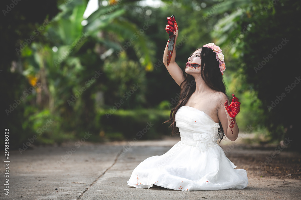 A female ghost or a zombie wearing a white dress with a bloody hand and ...