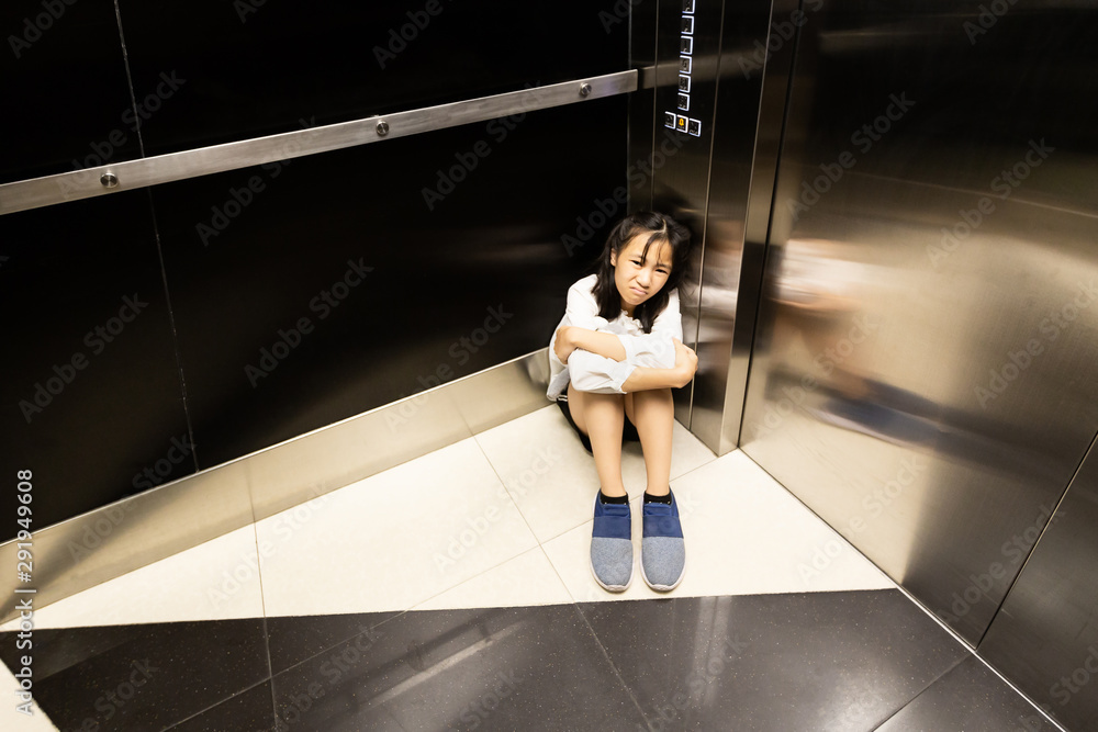 Asian child girl is stuck in an elevator,sad teenager girl sitting ...