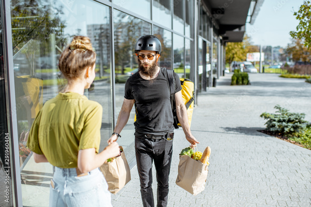 Young courier delivering fresh food from the supermarket to a young ...