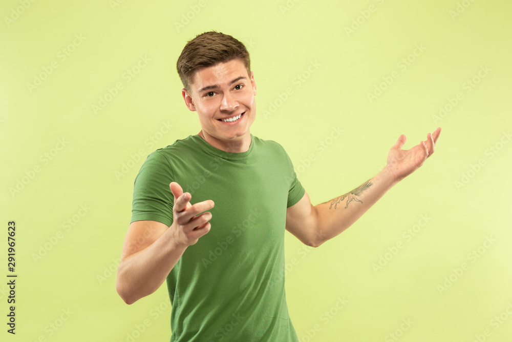 Caucasian young man's half-length portrait on green studio background ...