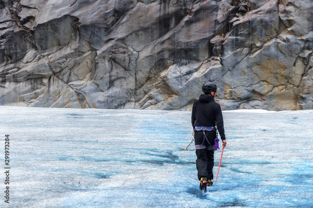 Lady on the blue glacier. She is holding ice climbing equipment.Walking ...