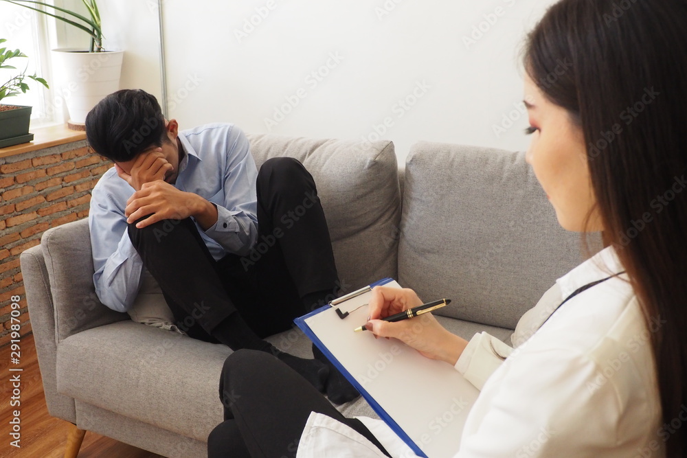 Asian professional female psychiatrist taking notes and giving advice ...