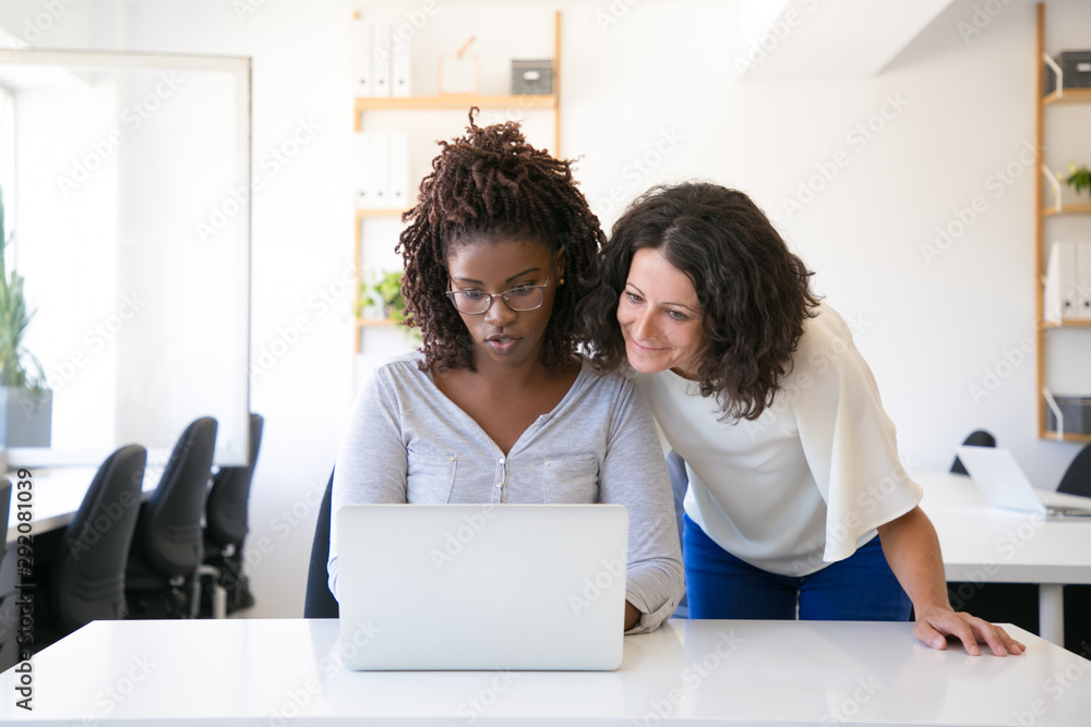 Excited female colleagues watching content on monitor together ...