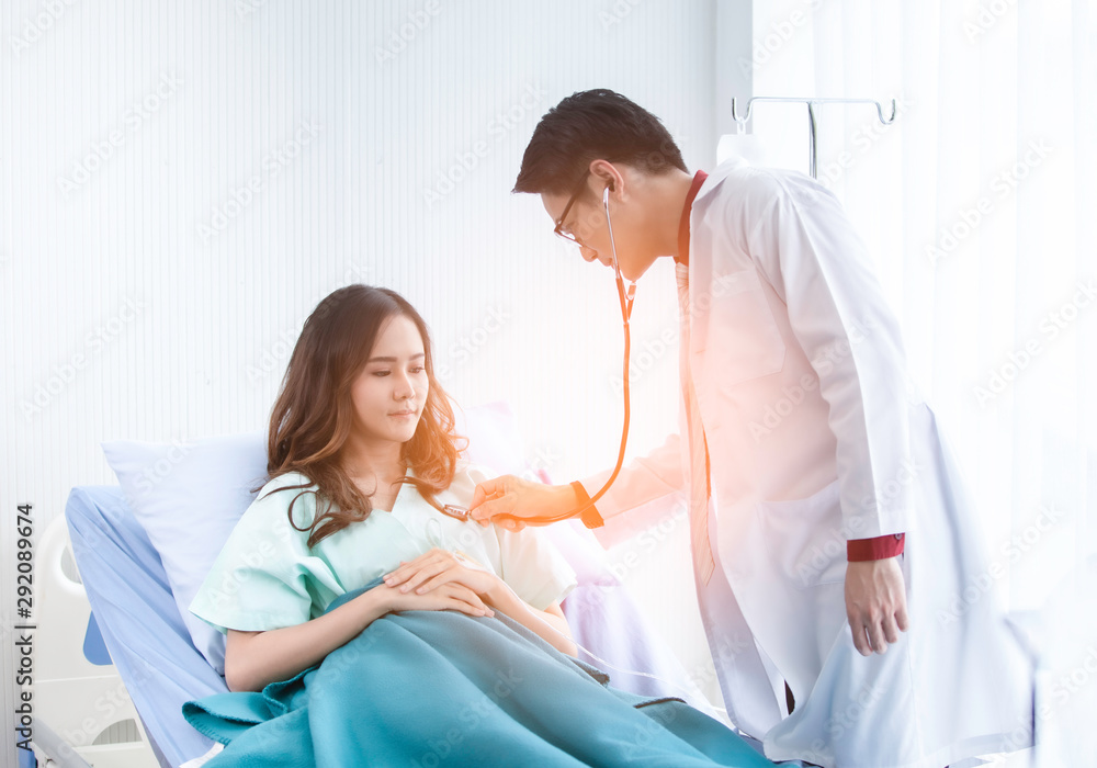 Hospitalized woman lying in bed while doctor checking examining his ...