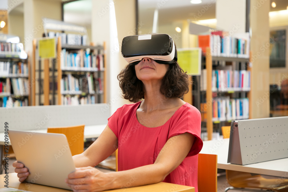 Adult female student using virtual technology for work on project in ...