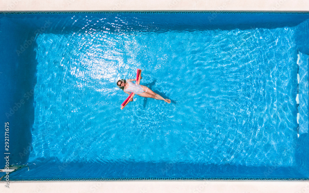 Zenith aerial view of a swimming pool. Young girl in a swimsuit ...