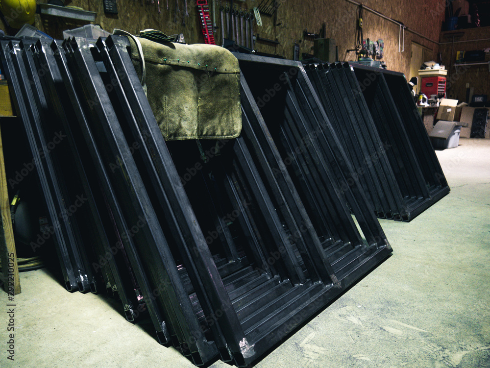 Metal frames stacked against a wall with a leather apron resting on top ...