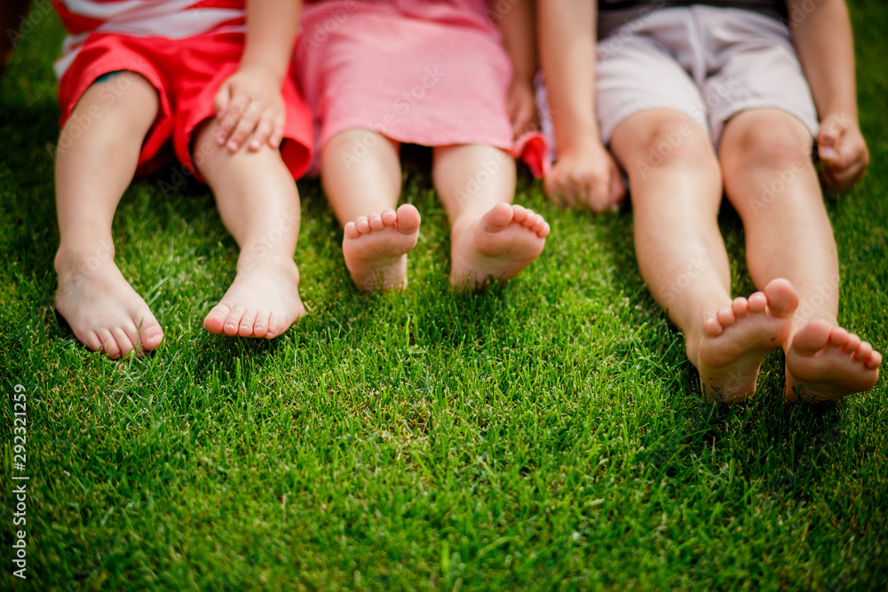 children's legs on the grass. bare legs of little girls sitting on the ...