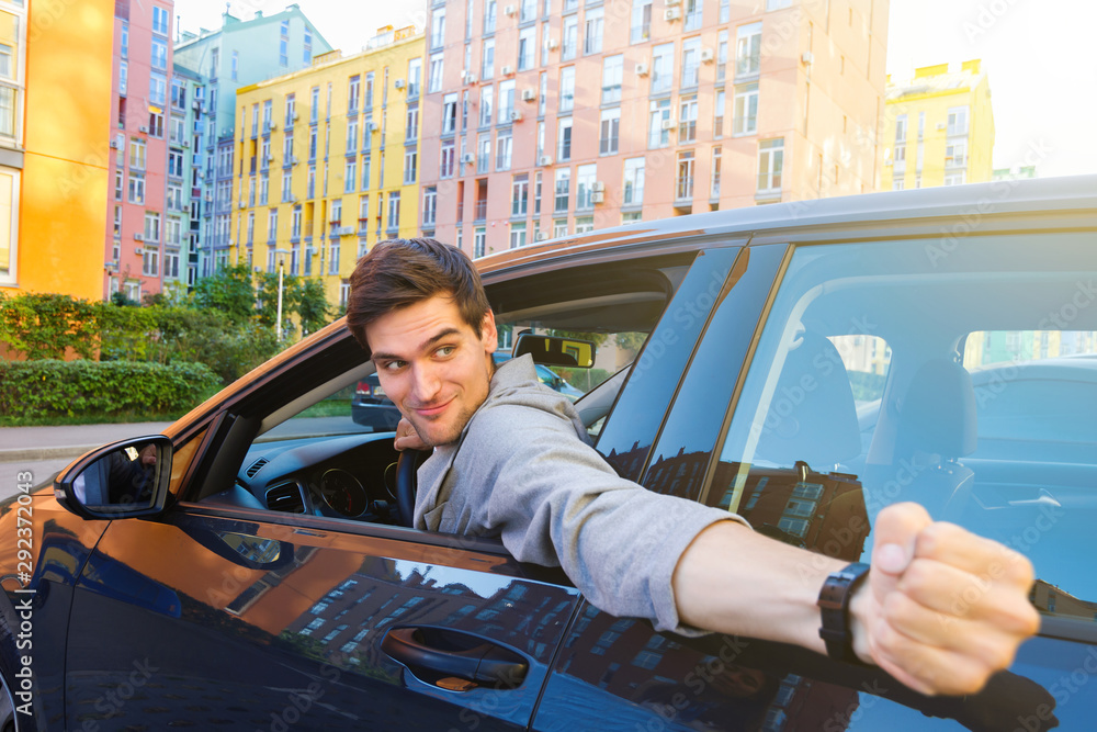 Annoyed young businessman is driving car. Man in gray suit is swearing ...