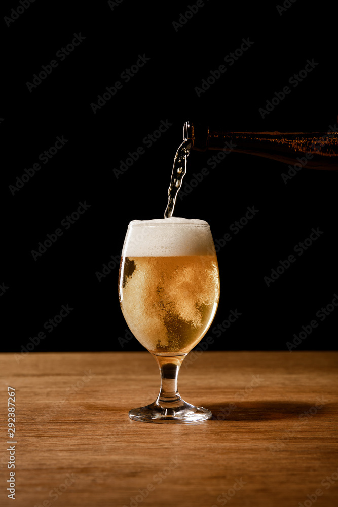 beer pouring from bottle in glass isolated on black Stock Photo | Adobe ...