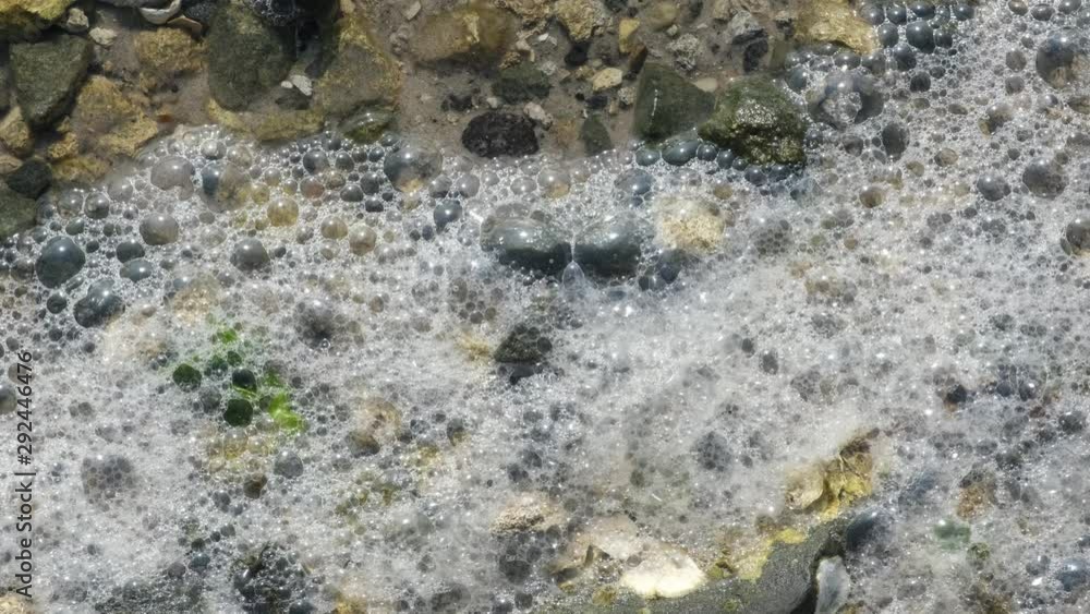 bubbles of sea foam float with the waves at an inlet bank in Topsail ...