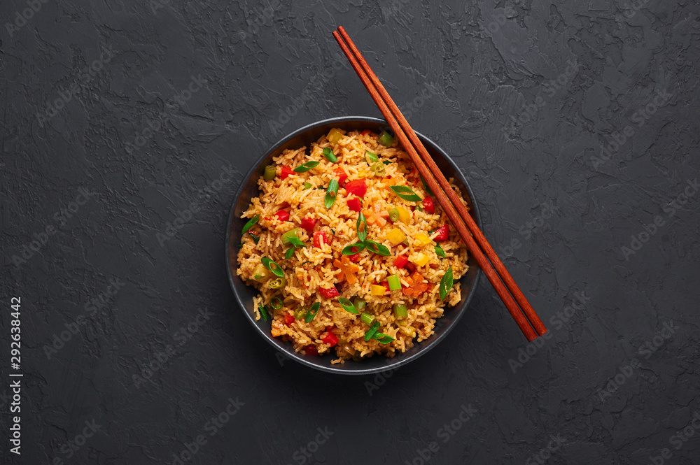 Veg Schezwan Fried Rice in black bowl at dark slate background ...