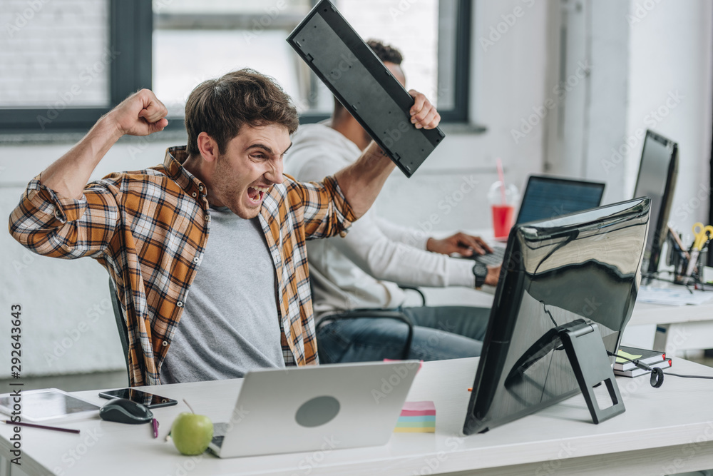 young irritated programmer holding keyboard and gesturing Stock Photo ...