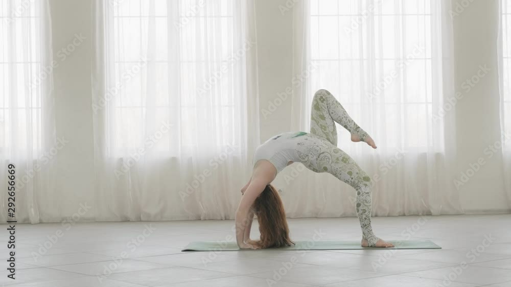 Woman practice yoga pose in studio with large windows. Attractive ...