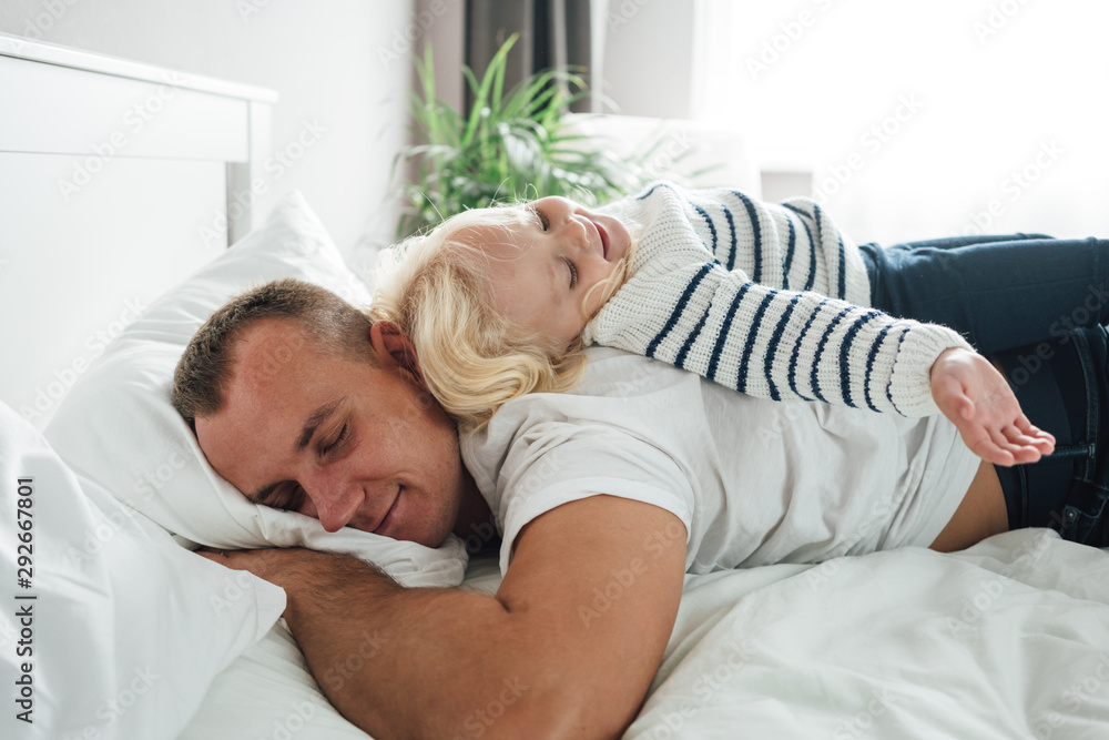Tired father sleep but his child interferes him. Young happy father ...