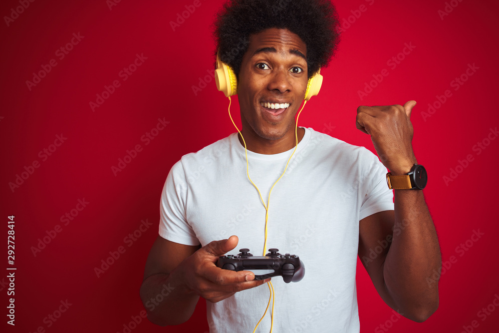 Afro gamer man playing video game using joystick headphones over ...