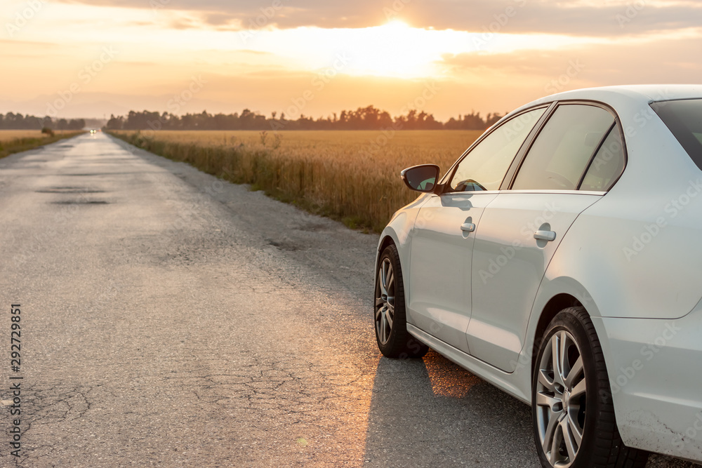 white car on country road next to yellow wheat field Stock Photo ...
