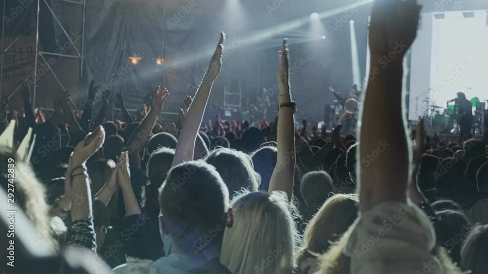 At night rock concert people having fun lifting hands up in air ...