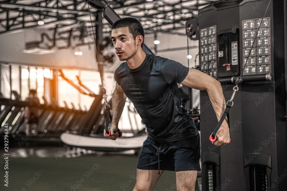 Young sportsman working out at the gym doing chest exercises on cable ...