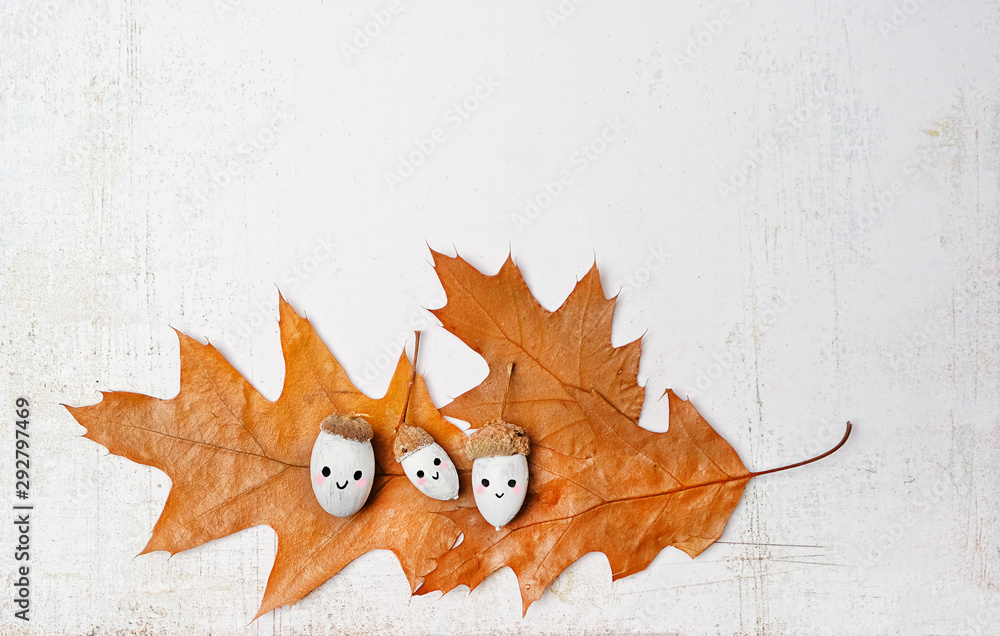 Happy little acorns and oak leaves on white table. funny acorns emotion ...