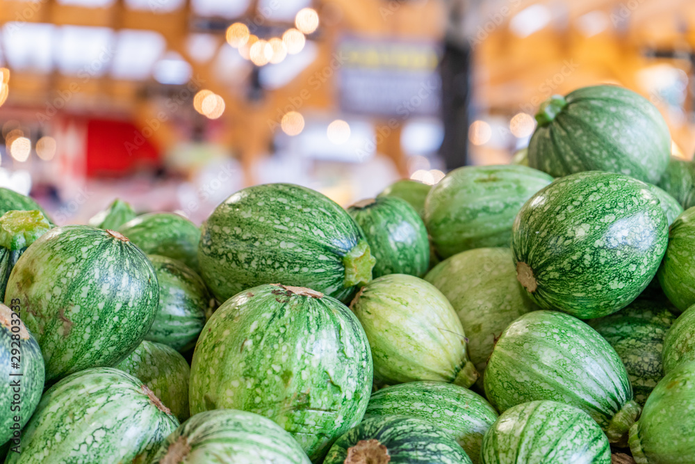 Round zucchini pile, being sold at a farmer's market. Also referred to ...