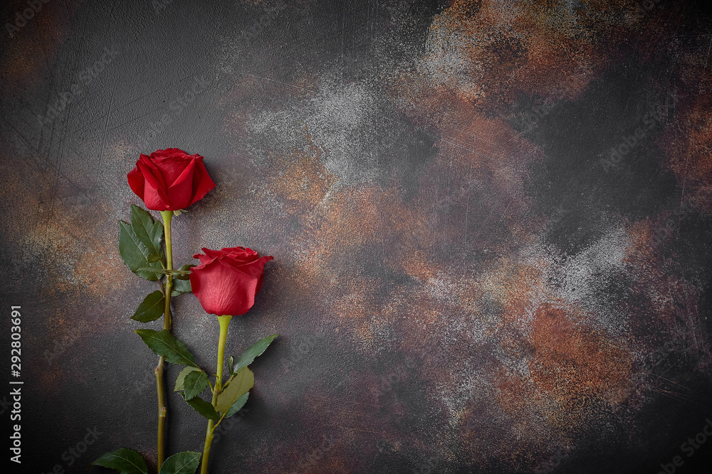Red roses lie on a textured spotted marble background. A sign of ...