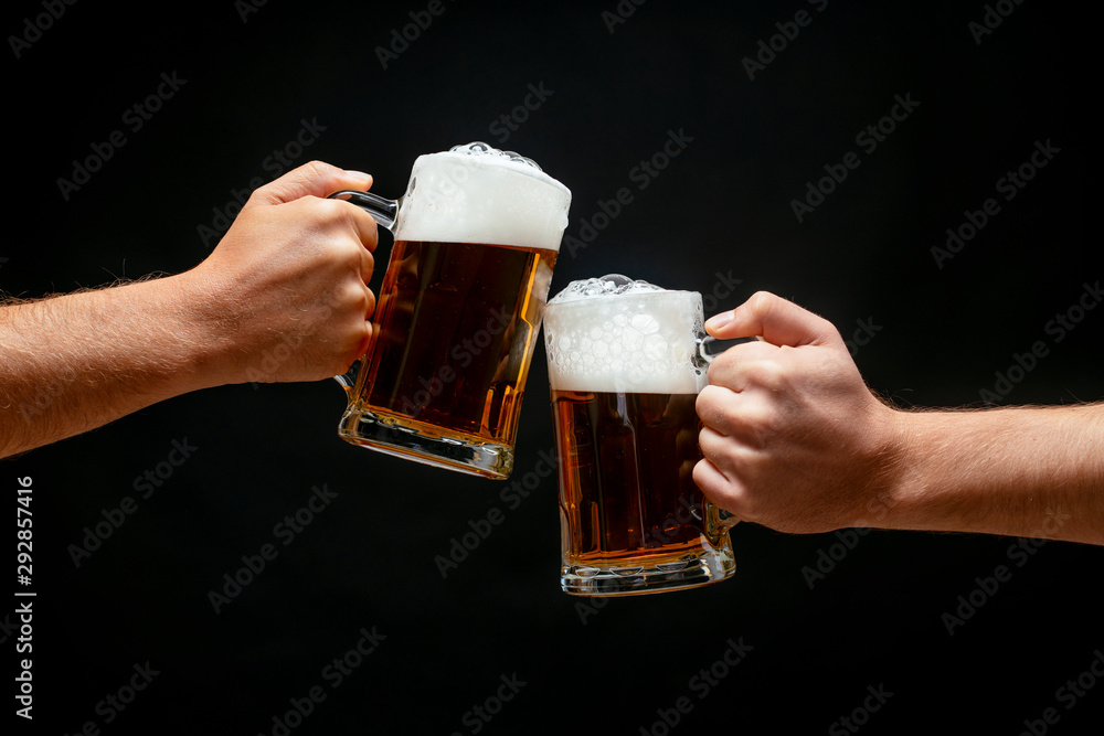 Hands toasting with beer on black background Stock Photo | Adobe Stock