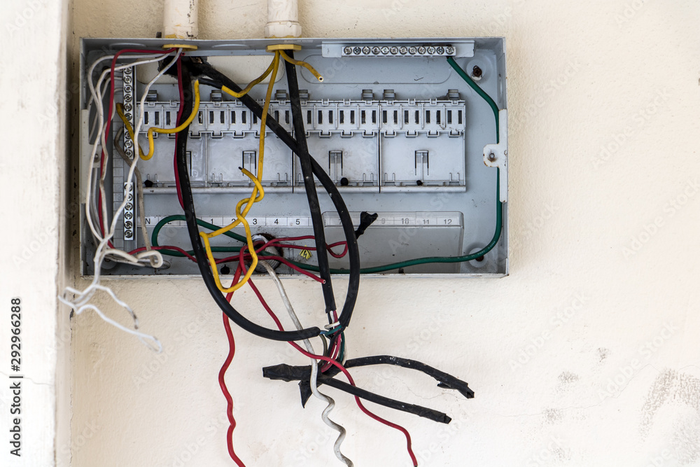 A open empty electricity fuse box with cables on white wall. Electrical ...