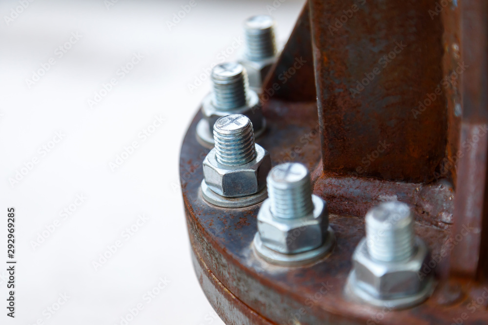 New galvanized bolts connect old rusty metal parts close-up on a light ...