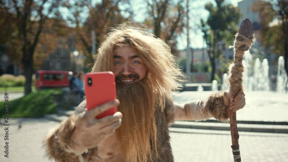 Portrait of wildman hunter-gatherer holding modern device making scary ...