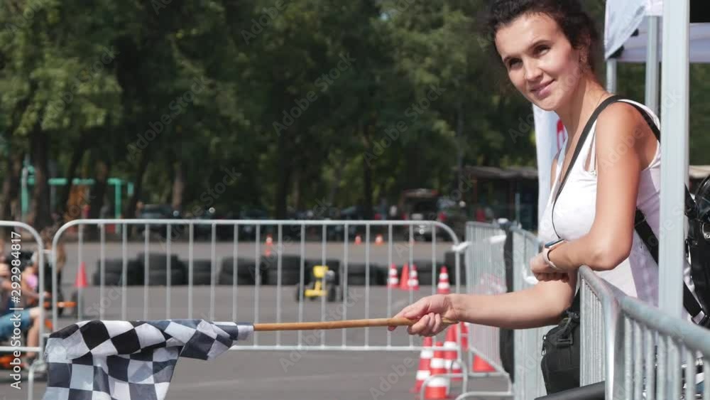 Attractive girl holding and waving checkered race flag on a kart race ...