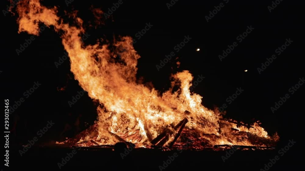 A large crowd of people celebrate an ethnic holiday by a giant bonfire ...