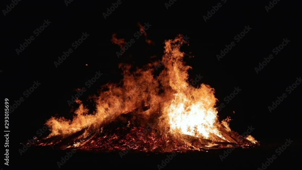 A large crowd of people celebrate an ethnic holiday by a giant bonfire ...