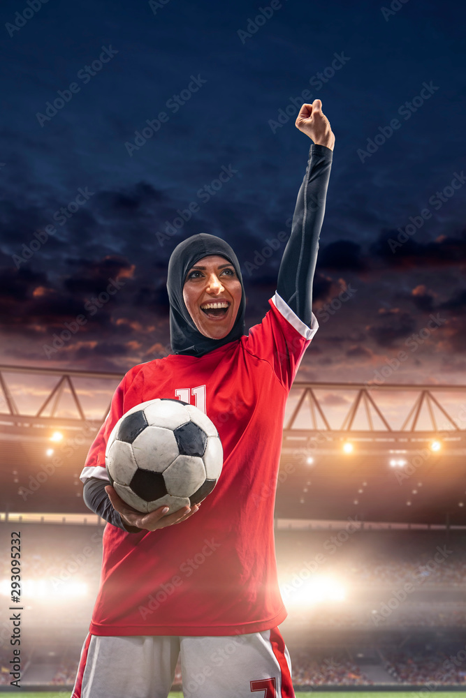 Female muslim soccer player in hijab standing with a ball on a ...