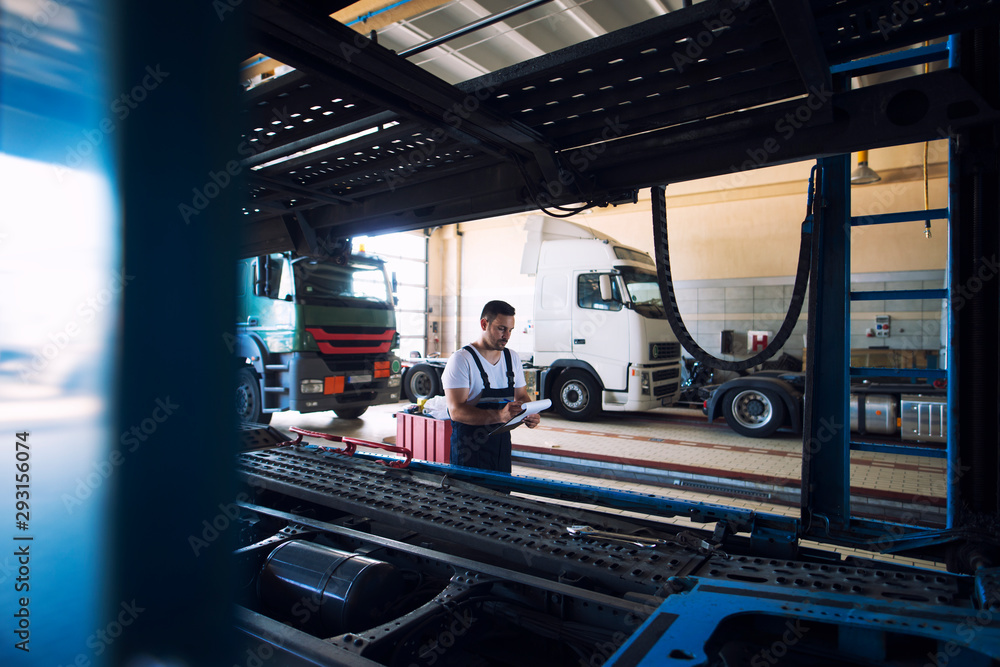 Truck repair shop. Vehicle mechanics doing checkup and preparing truck ...