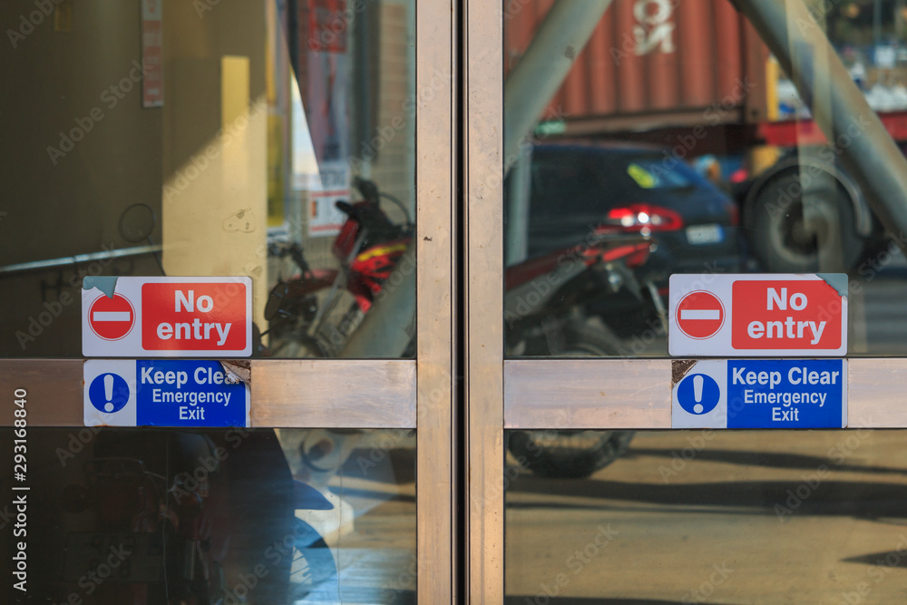 Sign on door NO ENTRY, KEEP CLEAR EMERGENCY EXIT, reflection on glass ...