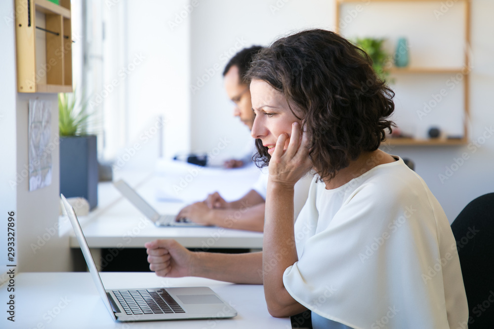 Excited focused female employee staring at computer monitor. Middle ...