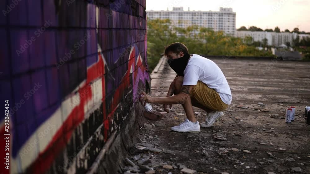 Guy painting graffiti on wall with an aerosol, side view. Talented ...