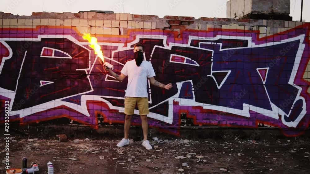 Scene of a graffiti urban artist in balaclava after painting the his ...