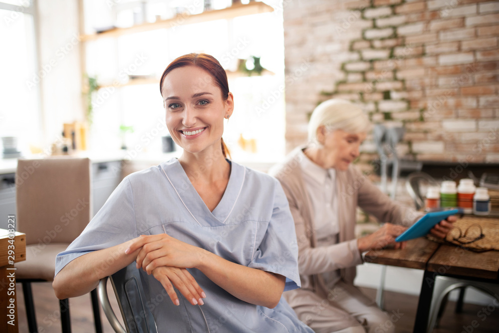 Beautiful hard-working caregiver wearing uniform smiling Stock Photo ...